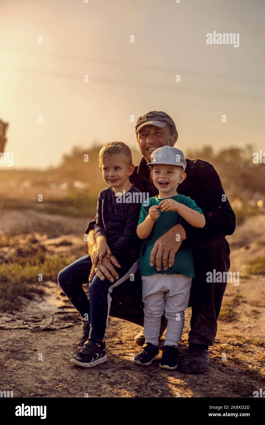 Grandfather hugging his grandsons during the corn harvest. A farmer ...