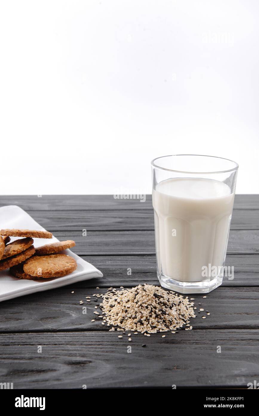 Sesame seed milk in a glass. White sesame seeds on the table. Raw diet ...