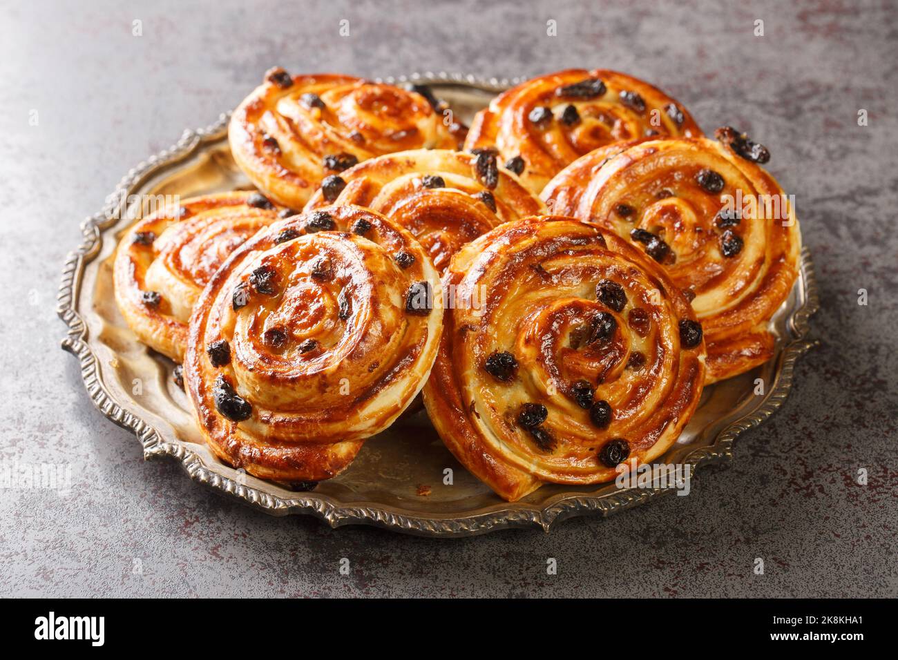 Homemade escargot buns with raisins and custard close-up in a plate ...
