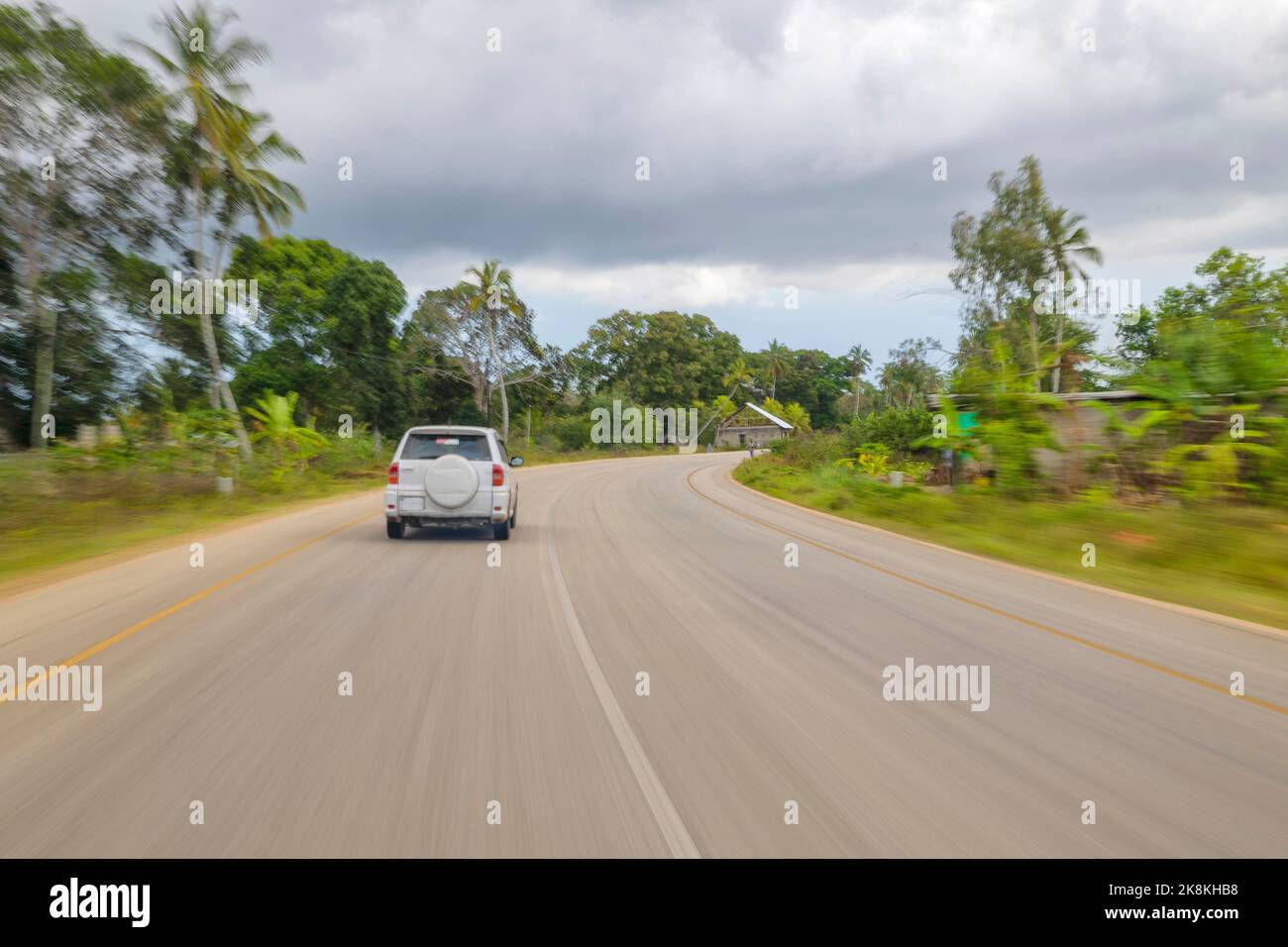 one car driving along the road of Zanzibar during a cloudy day ...