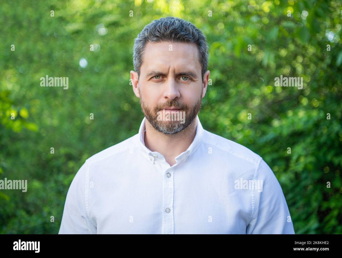 Portrait of handsome manager with unshaven face in white shirt natural ...