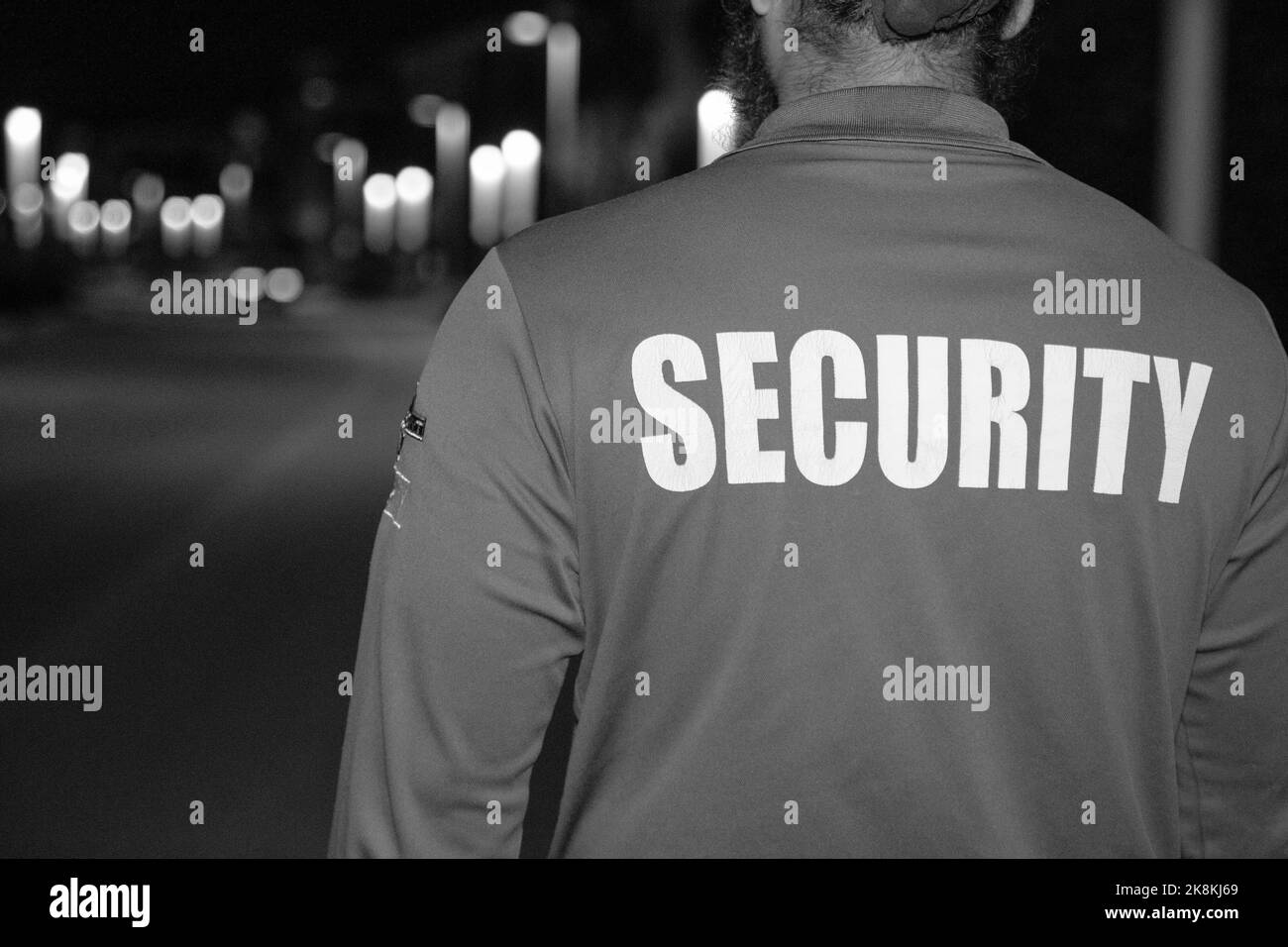 A grayscale of a person wearing a uniform with "security" on its back ...