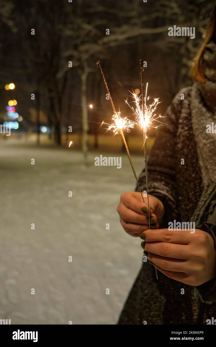 New year party burning sparkler closeup in female hand on black ...