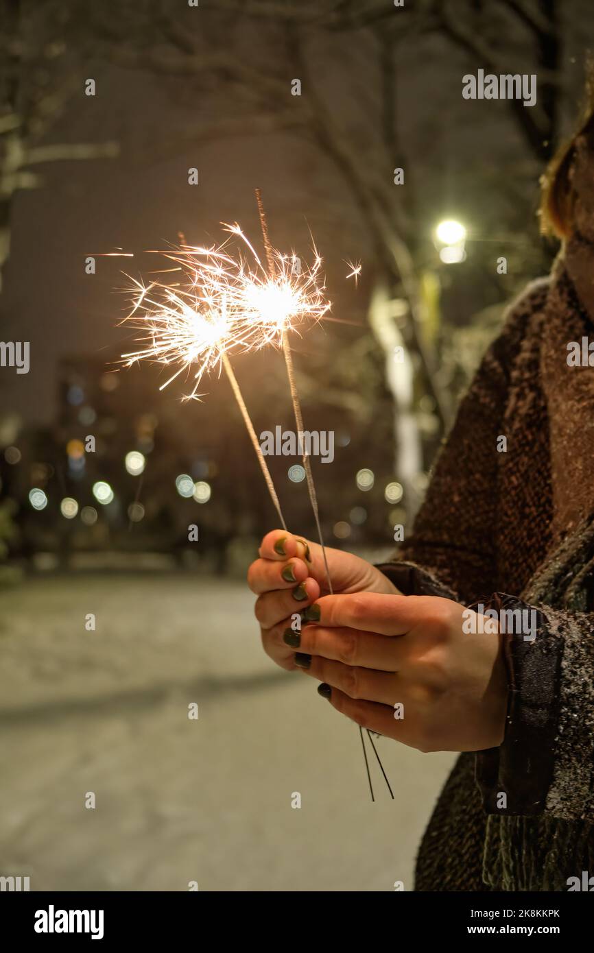 New year party burning sparkler closeup in female hand on black ...
