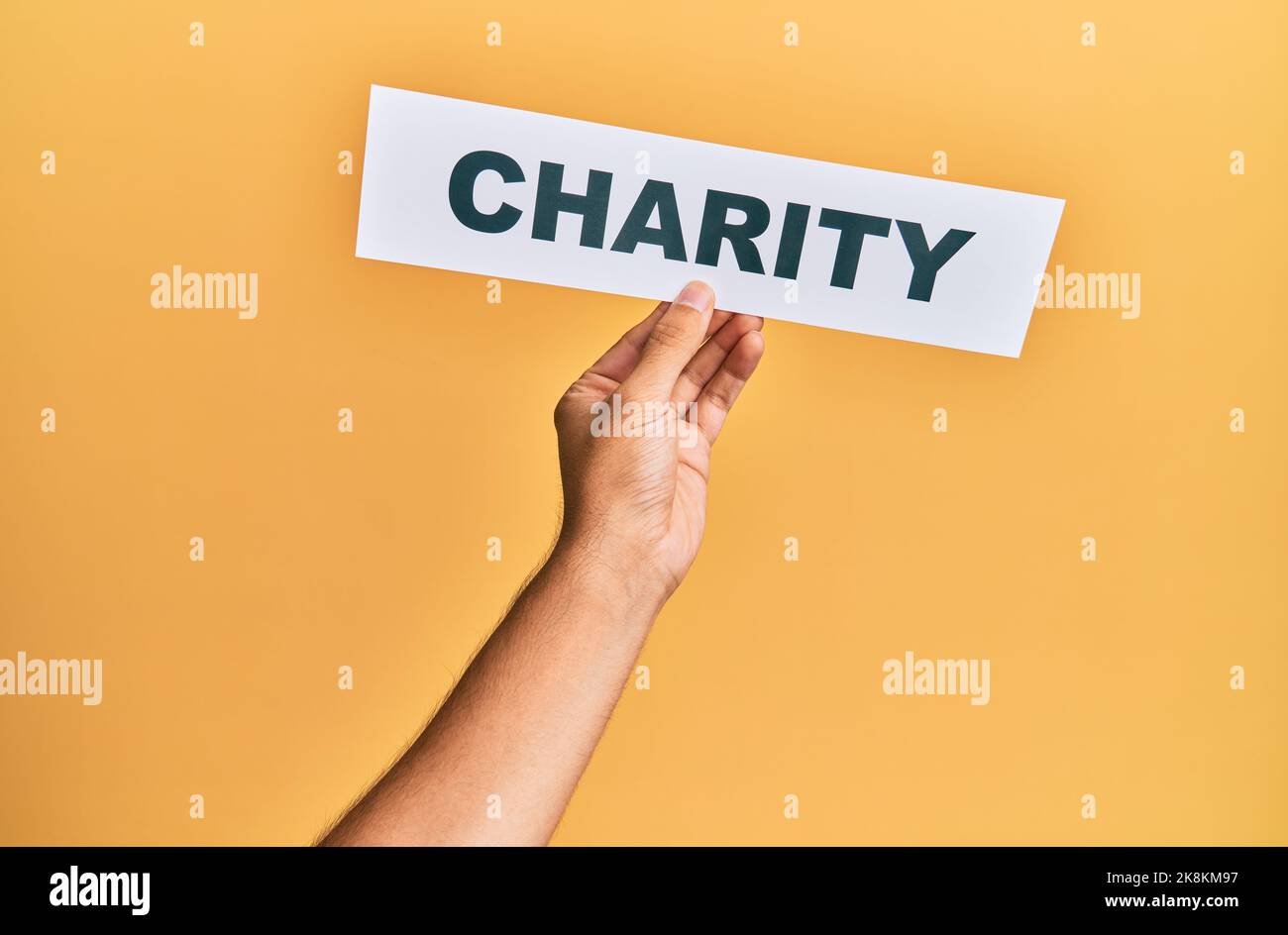Hand of caucasian man holding paper with charity word over isolated ...