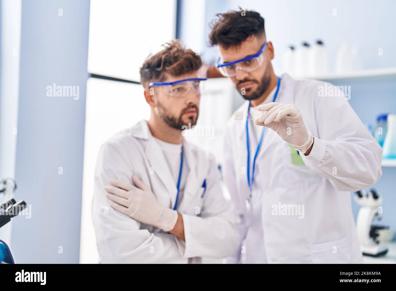 Young couple wearing scientist uniform holding sample at laboratory ...
