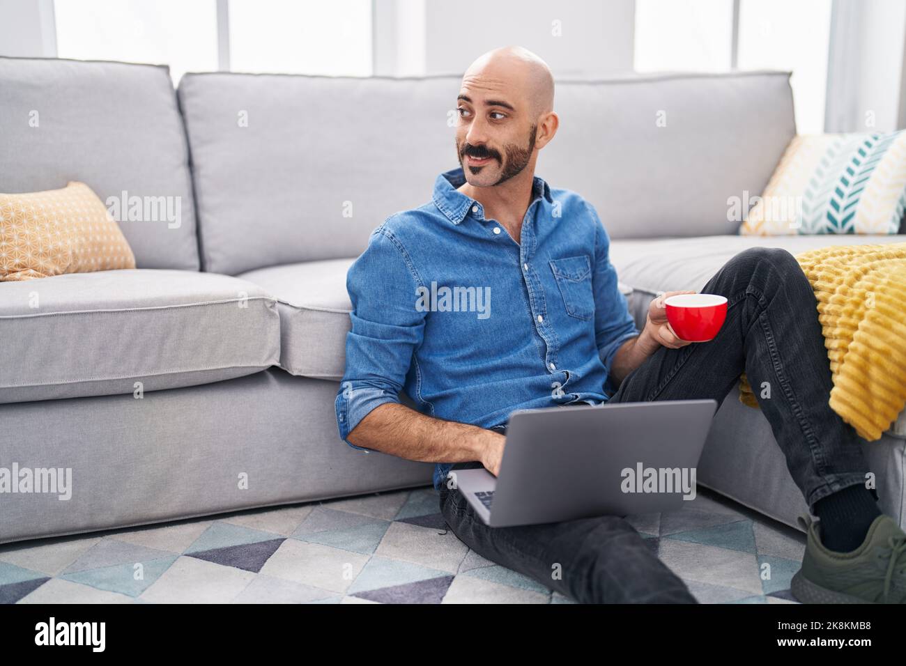 Young hispanic man using laptop drinking coffee at home Stock Photo - Alamy