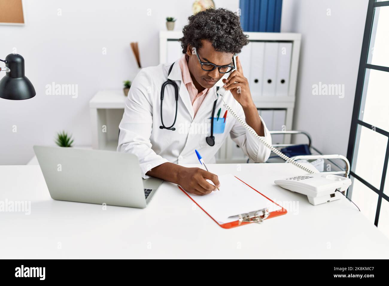 Young south east man wearing doctor uniform talking on the telephone at ...