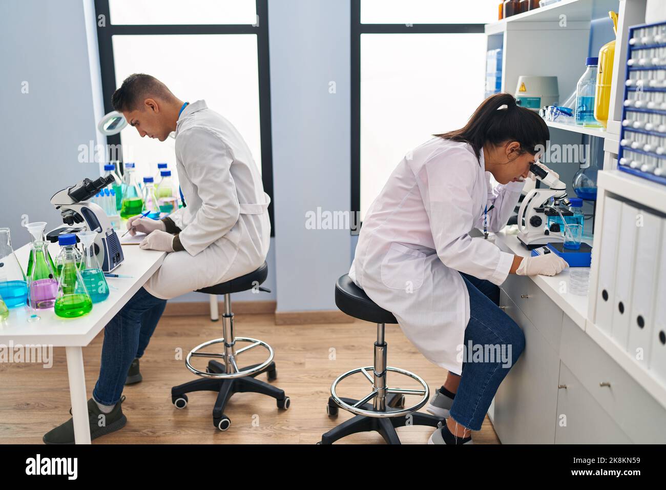 Man and woman scientists partners using microscope working at laboratory Stock Photo - Alamy