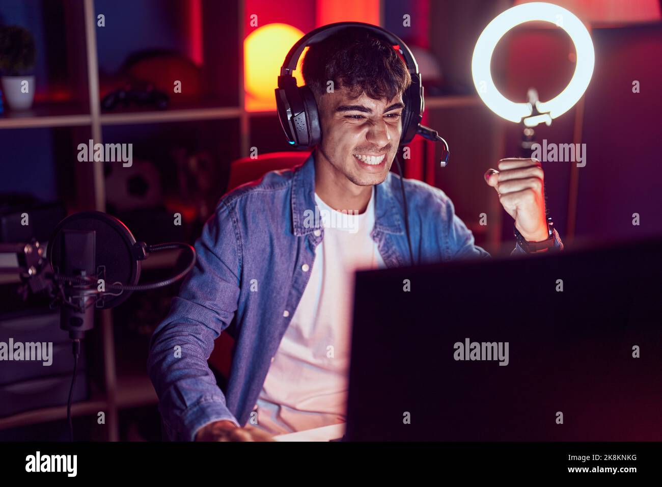 Young hispanic man streamer playing video game with winner expression ...