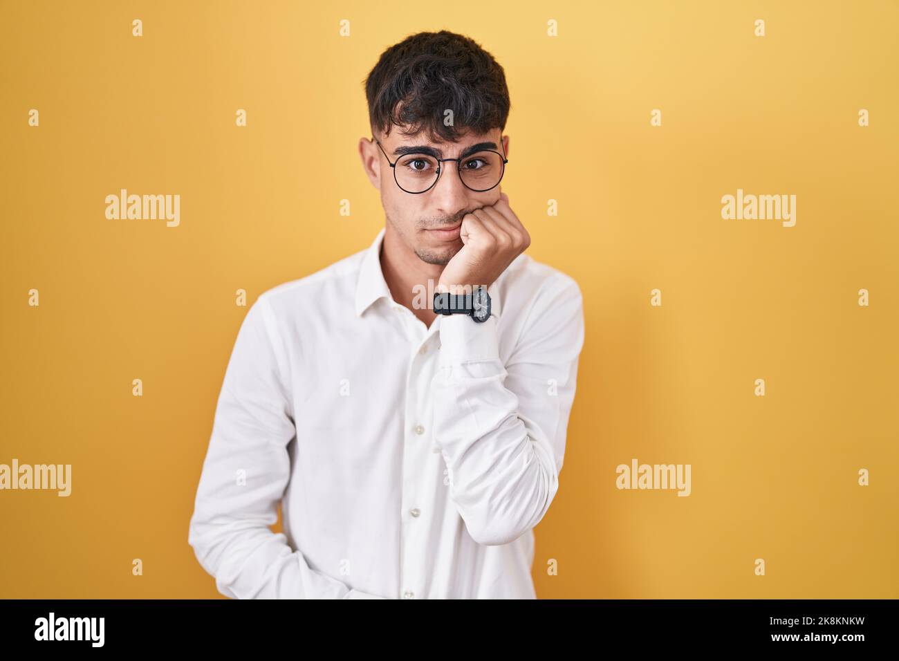 Young hispanic man standing over yellow background looking stressed and ...