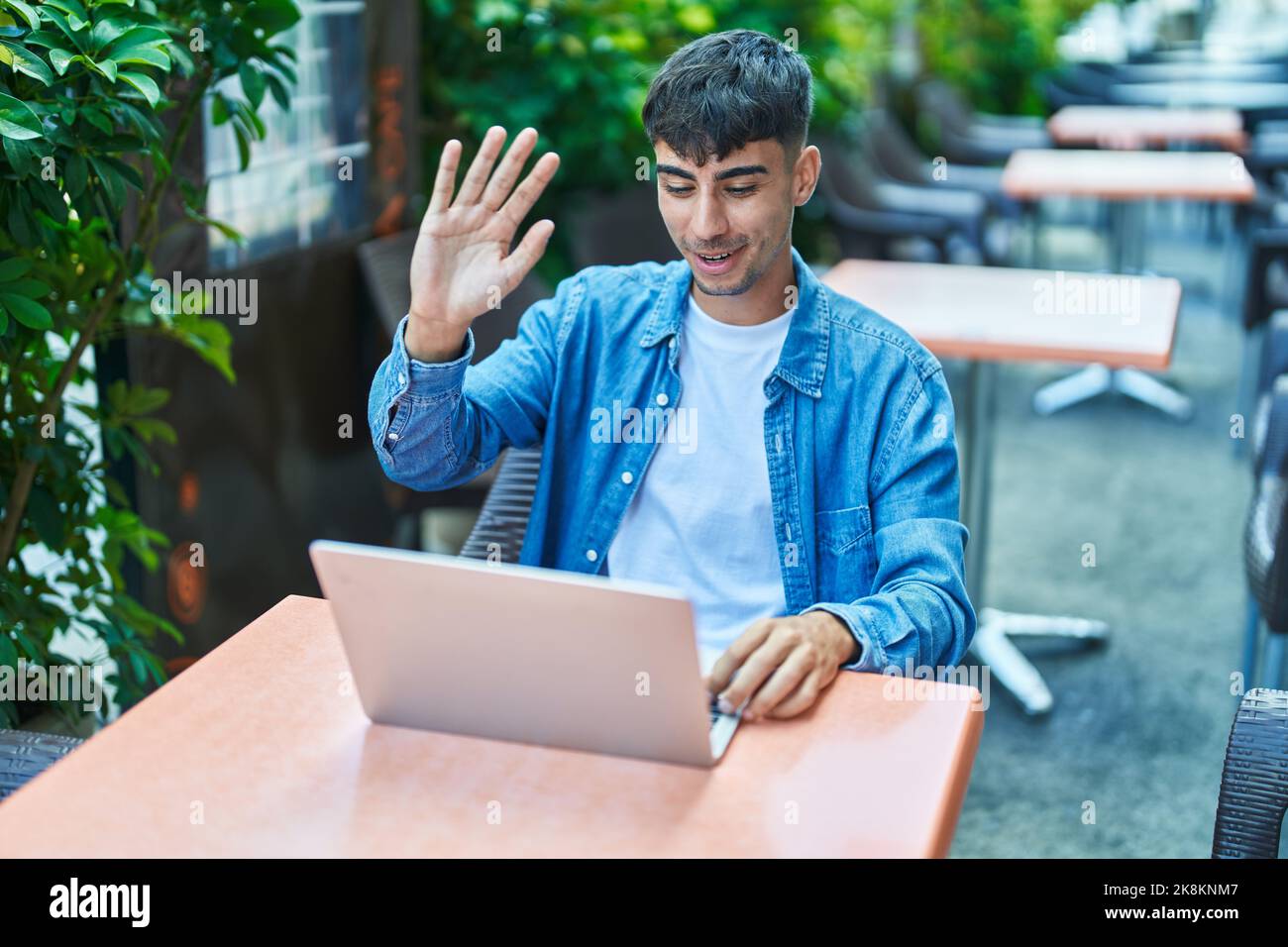 Young hispanic man having video call sitting on table at coffee shop ...