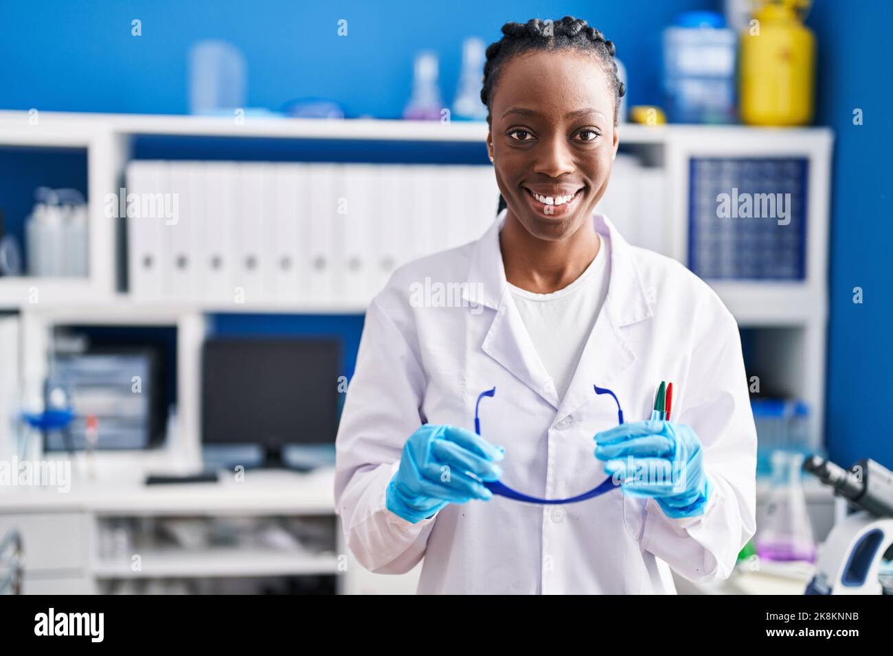 African american woman scientist smiling confident holding glasses at ...