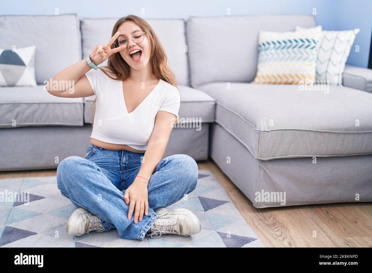 Young caucasian woman sitting on the floor at the living room doing ...