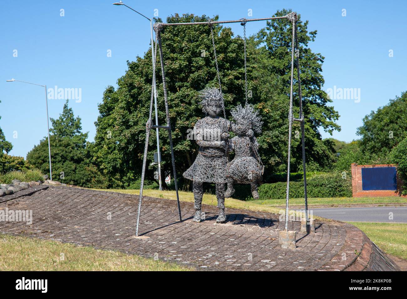 A wire sculpture of children on a swing on a roundabout in Rugby Stock ...