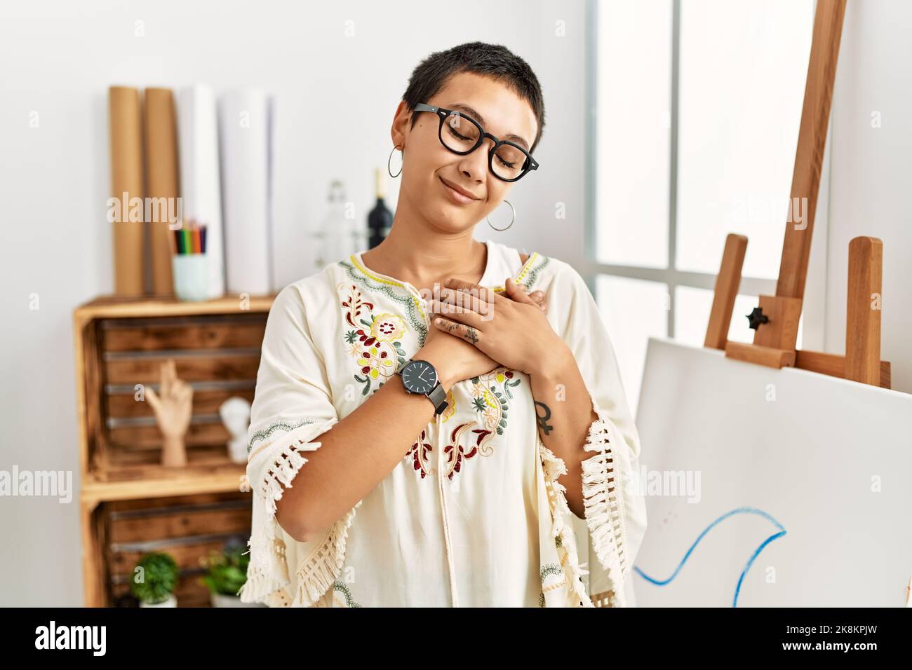 Young hispanic woman with short hair at art studio smiling with hands ...
