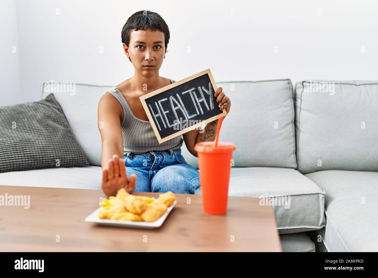 Young hispanic woman rejecting fast food holding healthy blackboard at ...