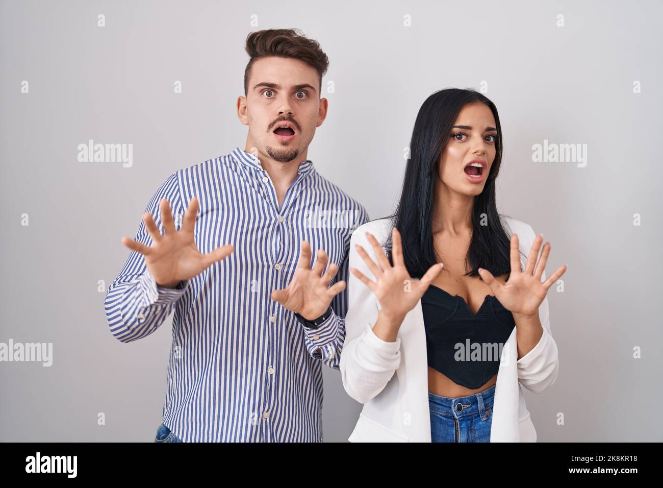 Young hispanic couple standing over white background afraid and ...
