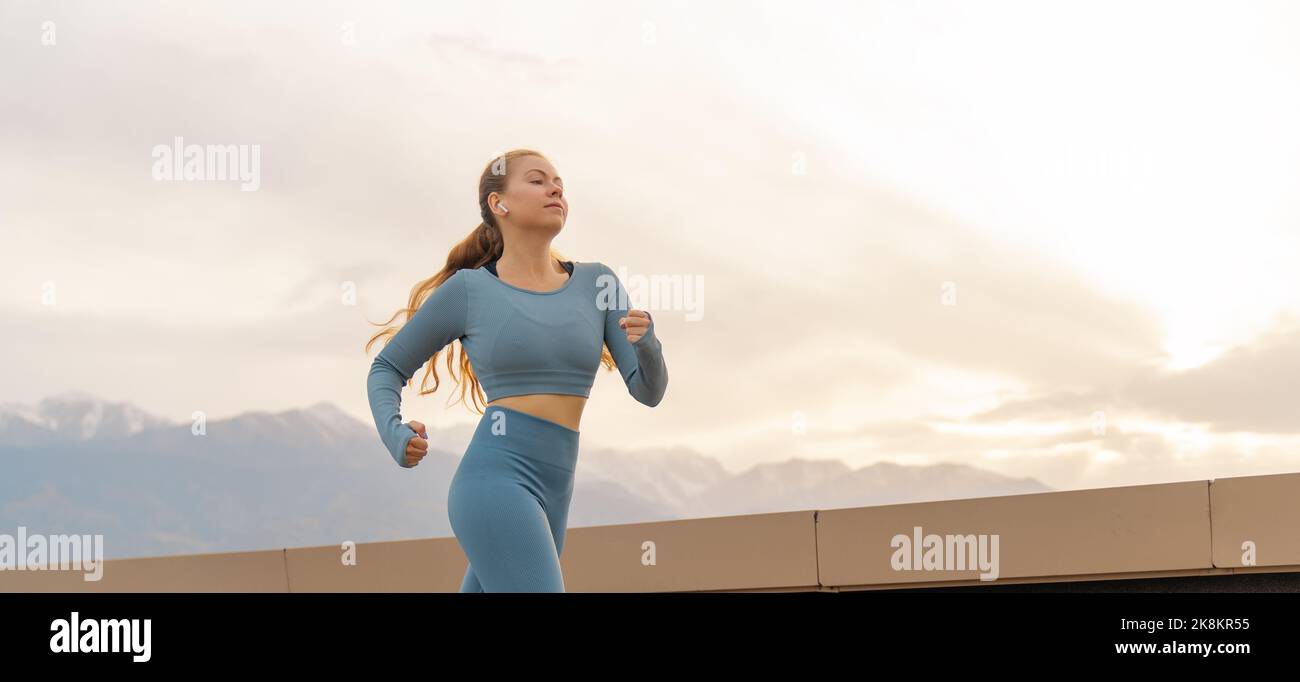Athletic woman is running on rooftop of parking, garage on sunset ...