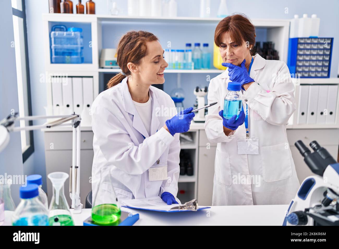 Two women scientists holding test tube writing on document at ...