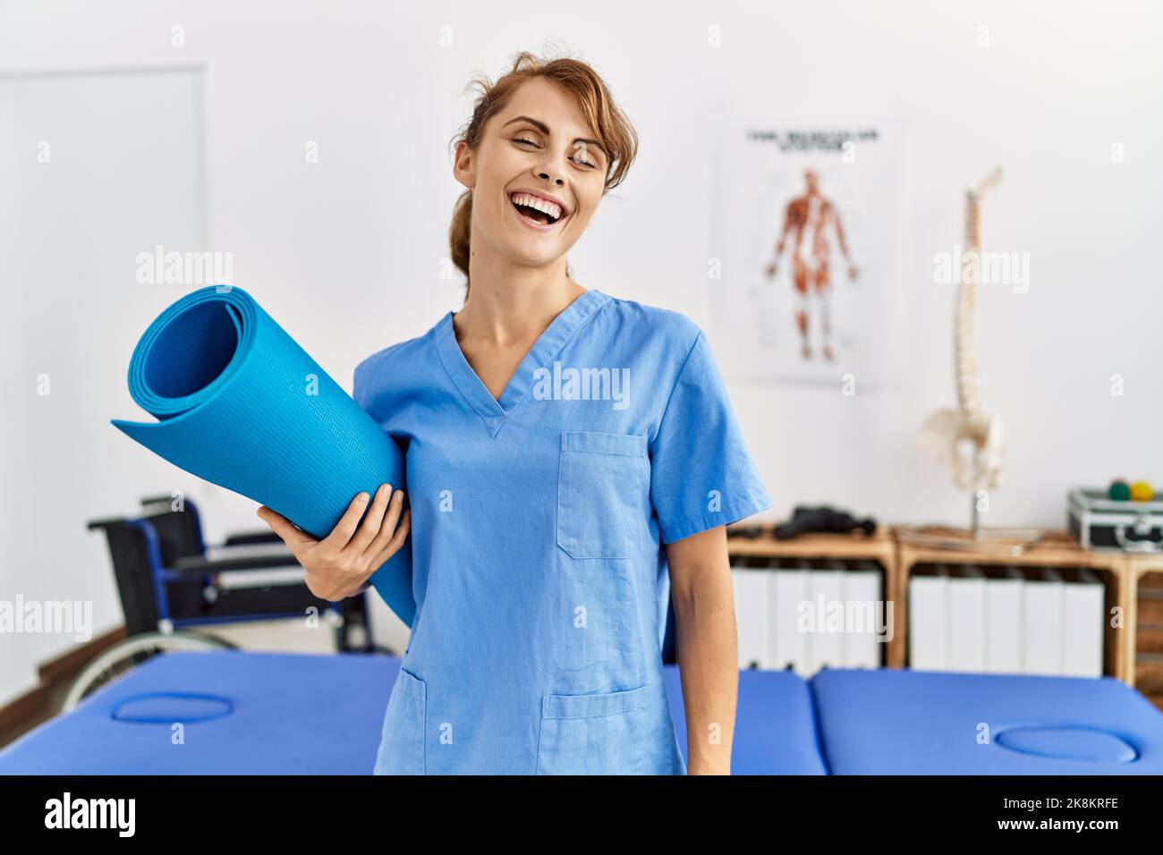 Young caucasian physio therapist girl smiling happy holding yoga mat at ...
