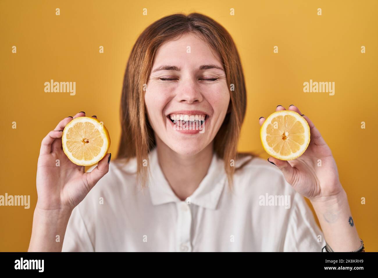 Beautiful woman holding lemons smiling and laughing hard out loud because funny crazy joke Stock ...