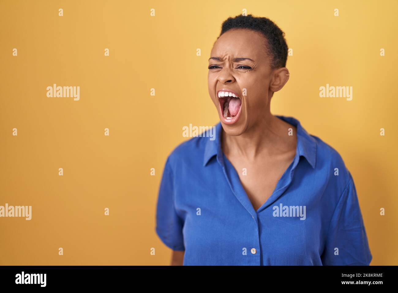 African american woman standing over yellow background angry and mad ...