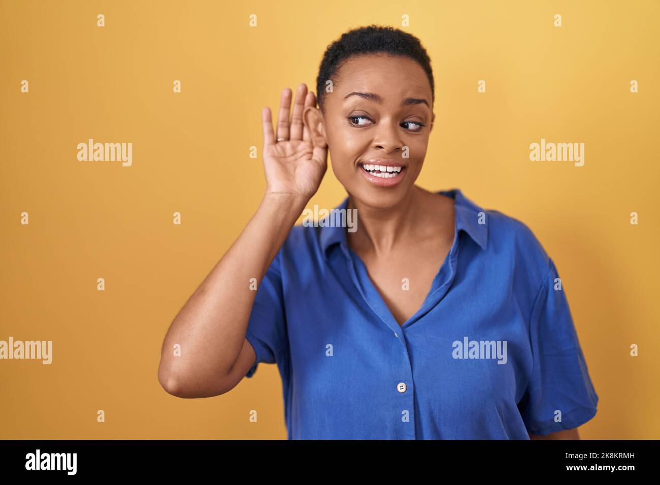African american woman standing over yellow background smiling with ...