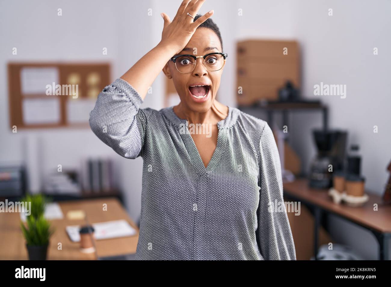 African american woman working at the office wearing glasses surprised ...