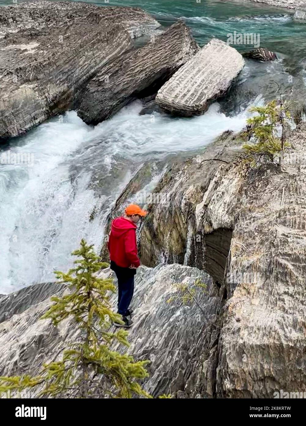 A boy standing on a rock near the raging waterfall Stock Photo - Alamy