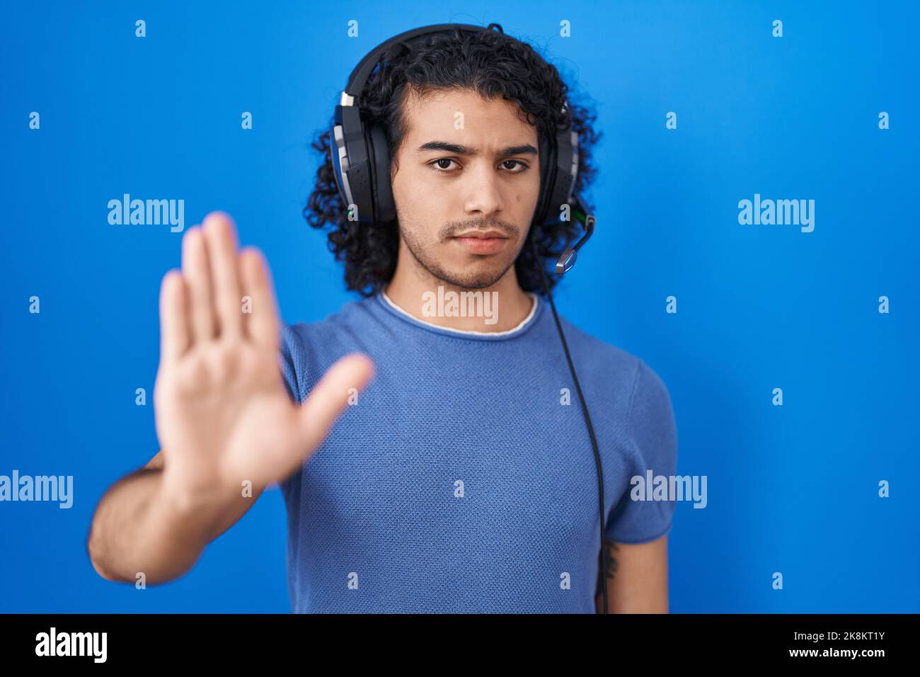 Hispanic man with curly hair listening to music using headphones doing ...