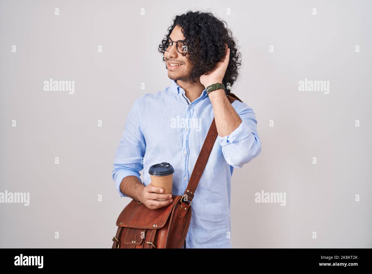 Hispanic man with curly hair drinking a cup of take away coffee smiling ...