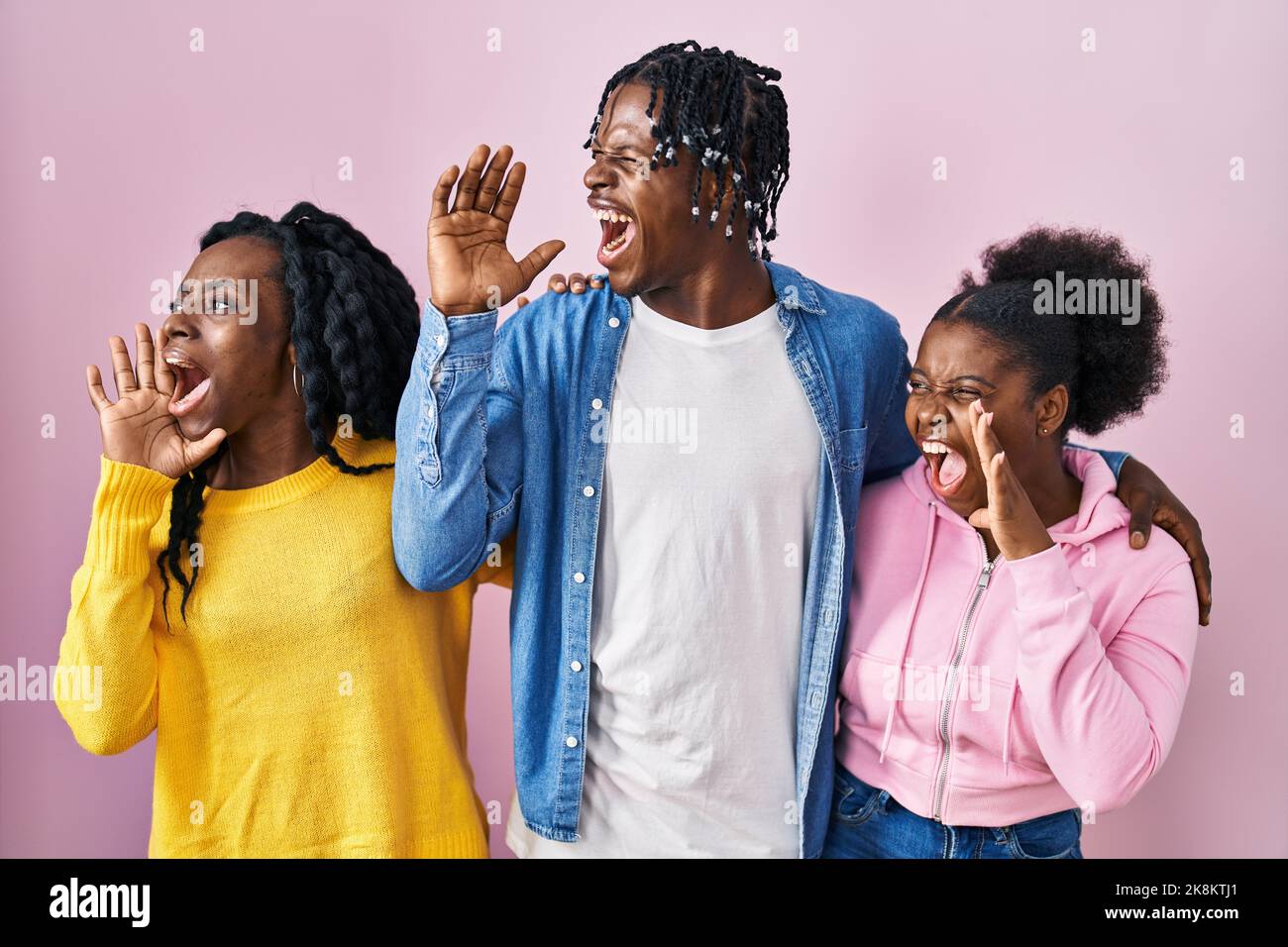 Group of three young black people standing together over pink ...