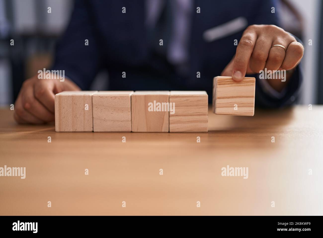 Young latin man business worker sitting on table with wooden cubes at ...