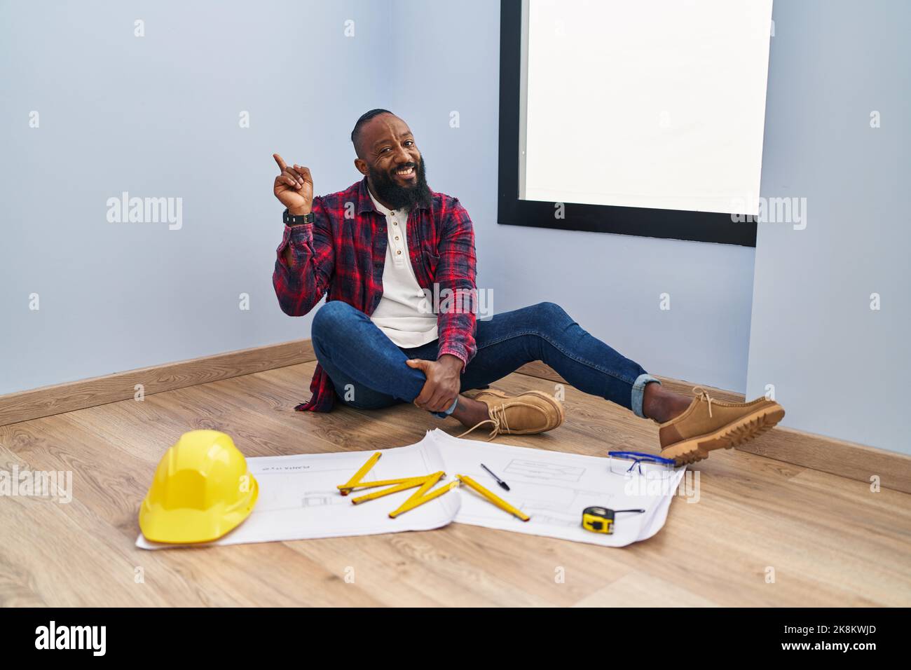 African american man sitting on the floor at new home looking at ...