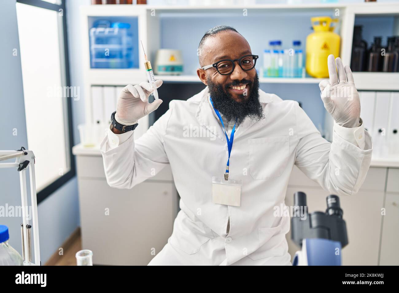 African american man working at scientist laboratory holding syringe ...