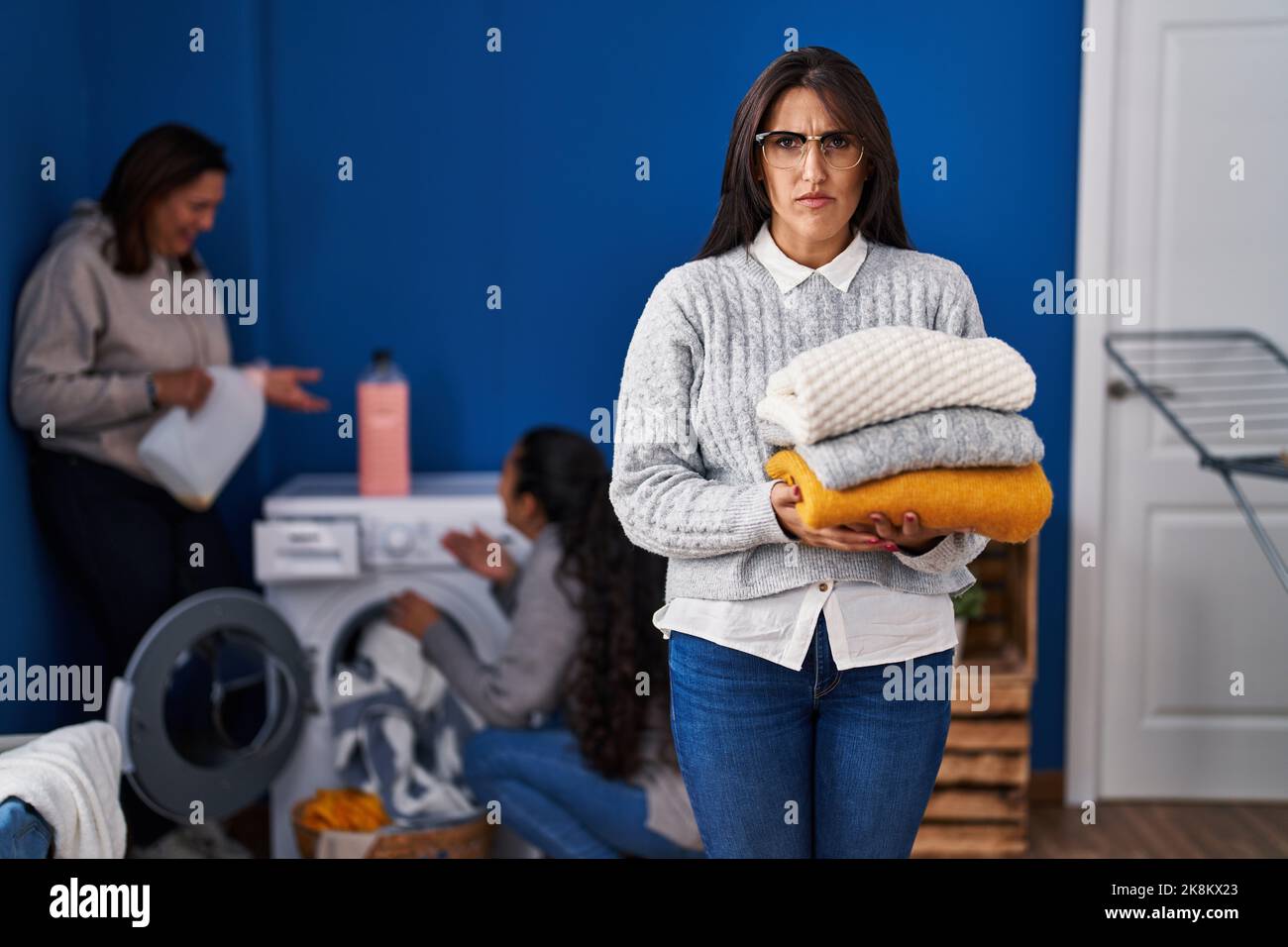 Three women doing laundry at home skeptic and nervous, frowning upset ...