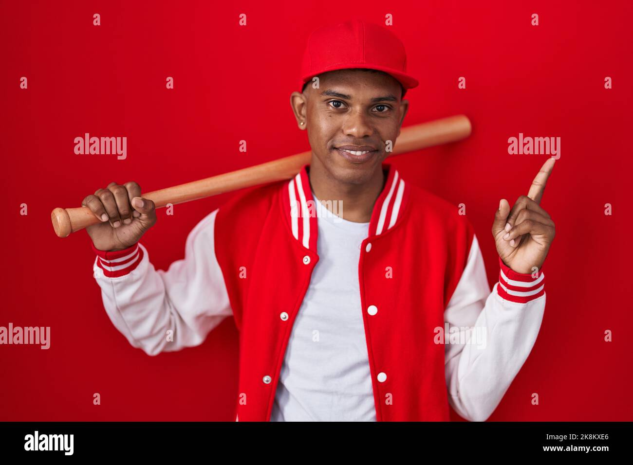 Young hispanic man playing baseball holding bat with a big smile on ...