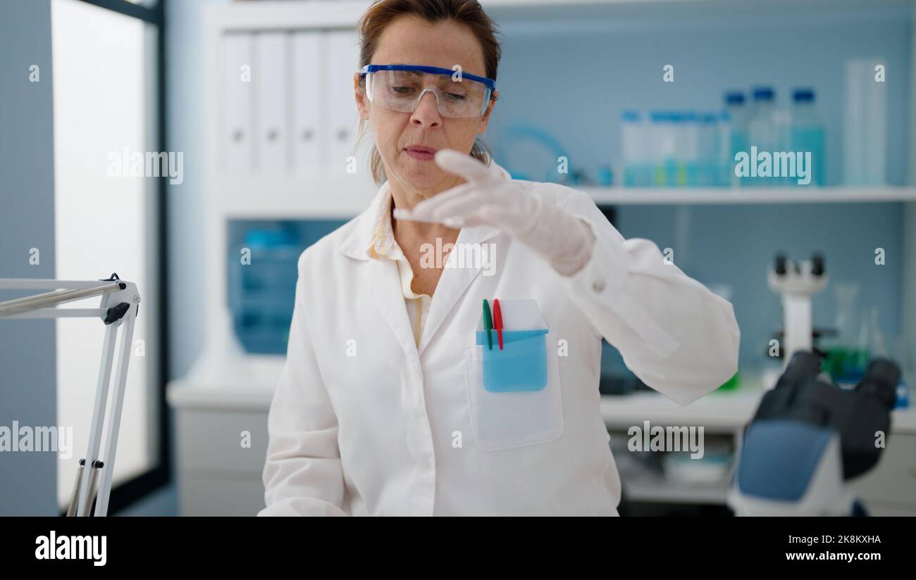 Middle age hispanic woman wearing scientist uniform working at ...