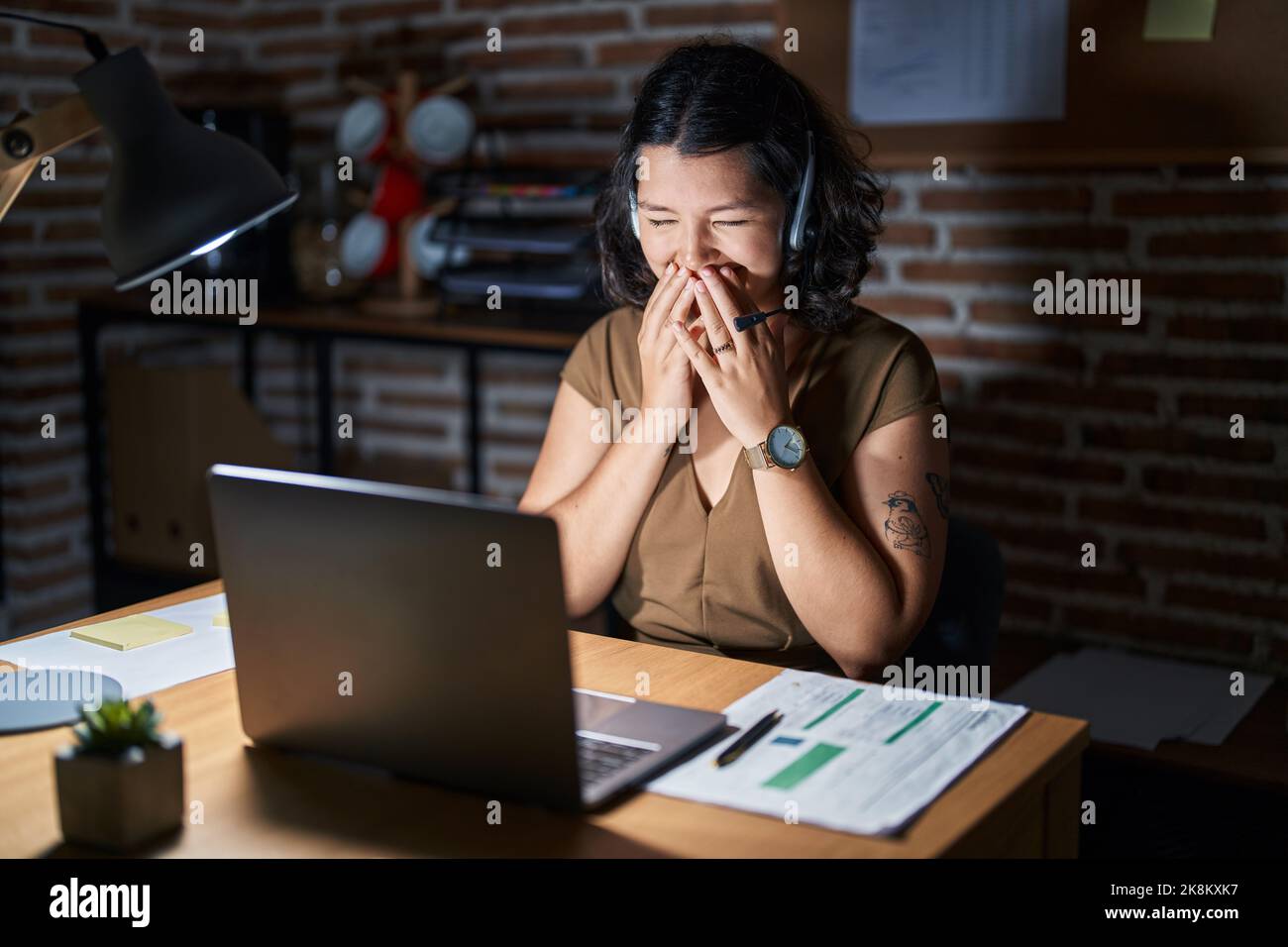 Young hispanic woman working at the office at night laughing and ...