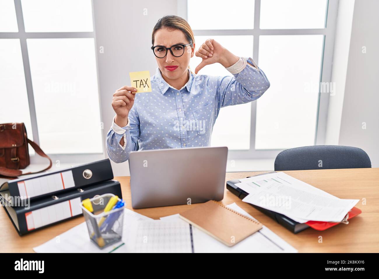Young hispanic business woman at the office calculating taxes with ...