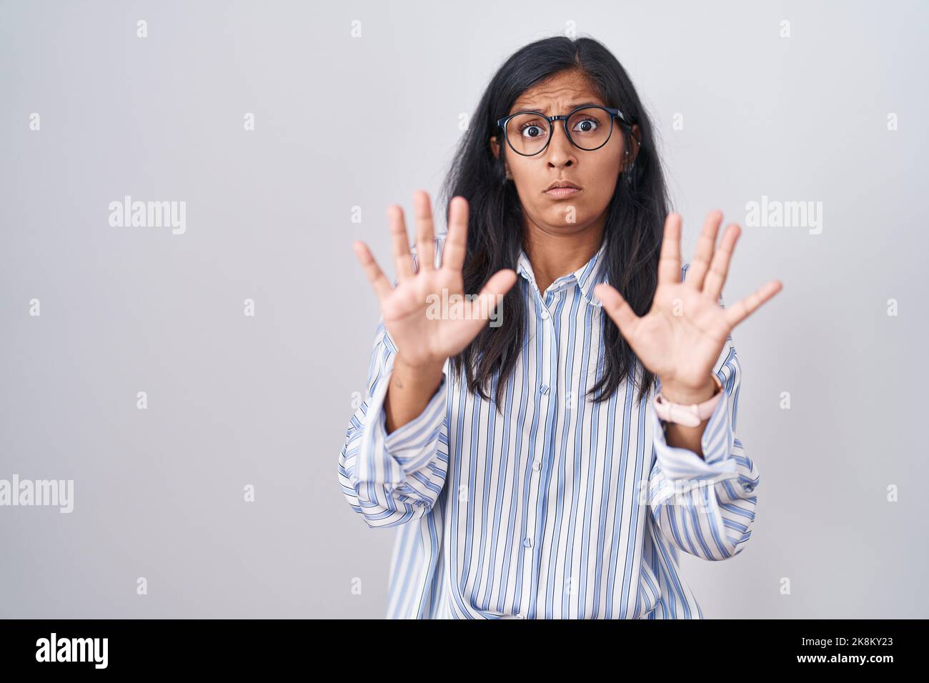 Young hispanic woman wearing glasses moving away hands palms showing ...