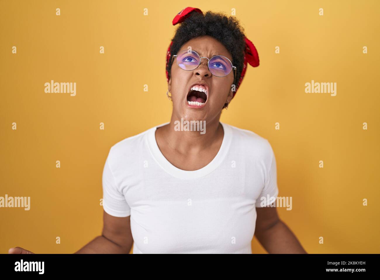 Young african american woman standing over yellow background angry and ...