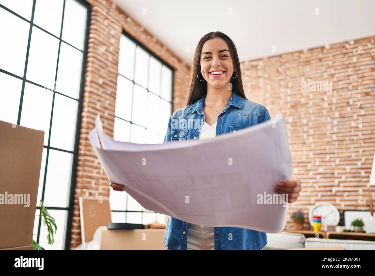 Young beautiful hispanic woman architect smiling confident reading ...