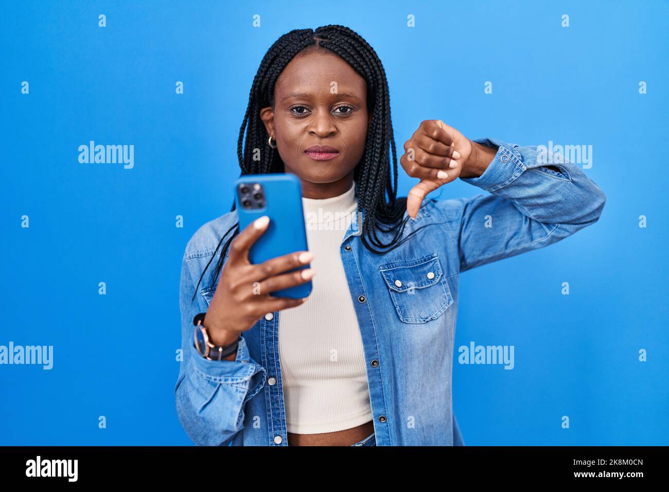 African woman with braids using smartphone typing message with angry ...