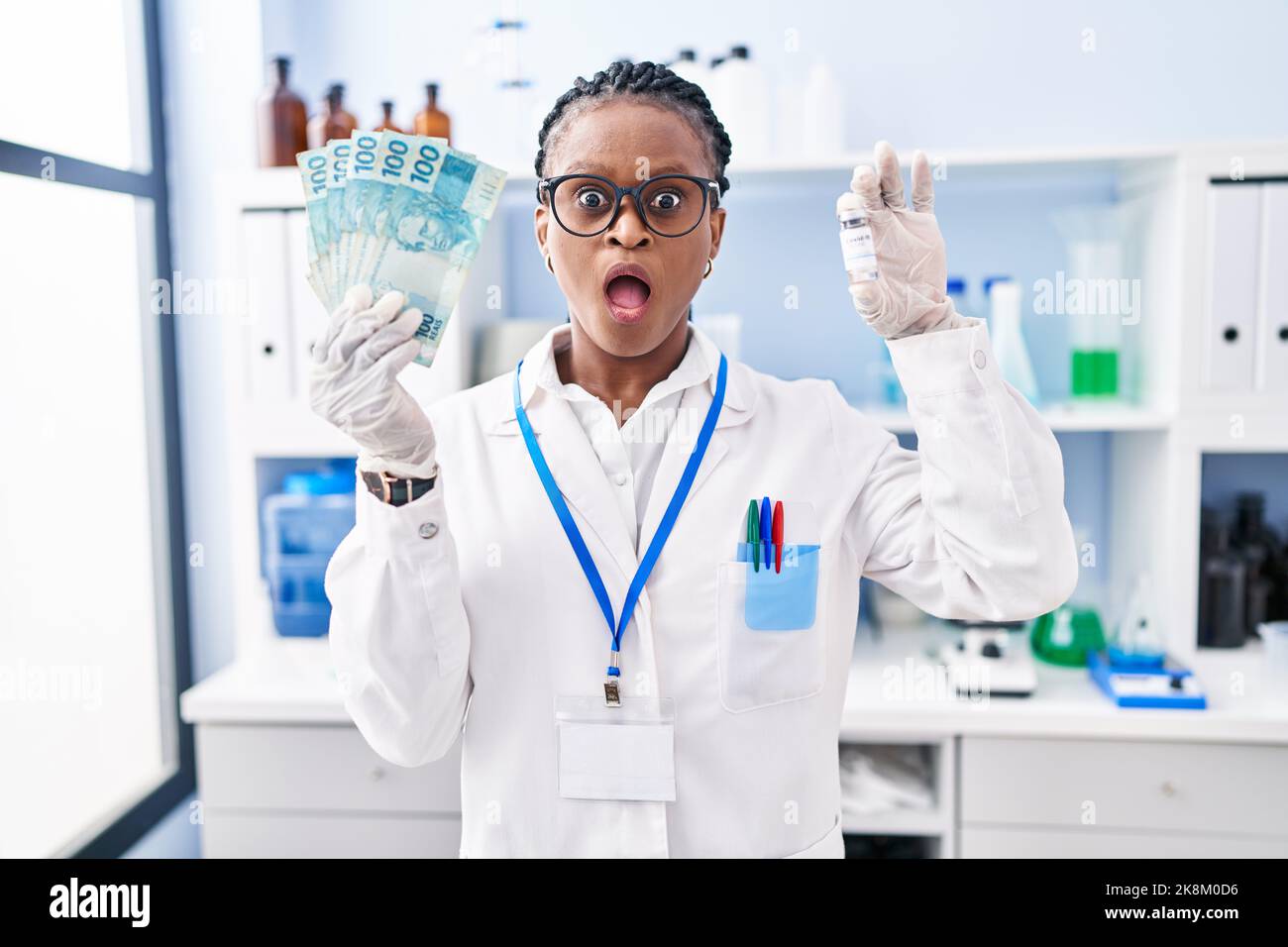 African woman with braids working at scientist laboratory holding money ...
