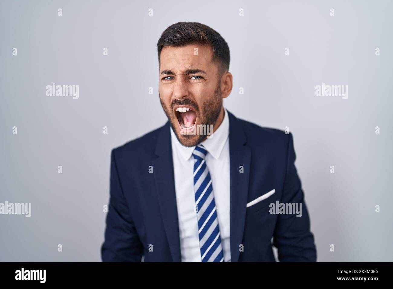 Handsome hispanic man wearing suit and tie angry and mad screaming ...