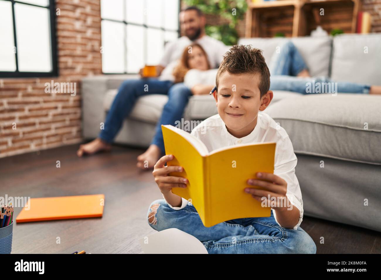 Family watching tv and son reading book at home Stock Photo - Alamy