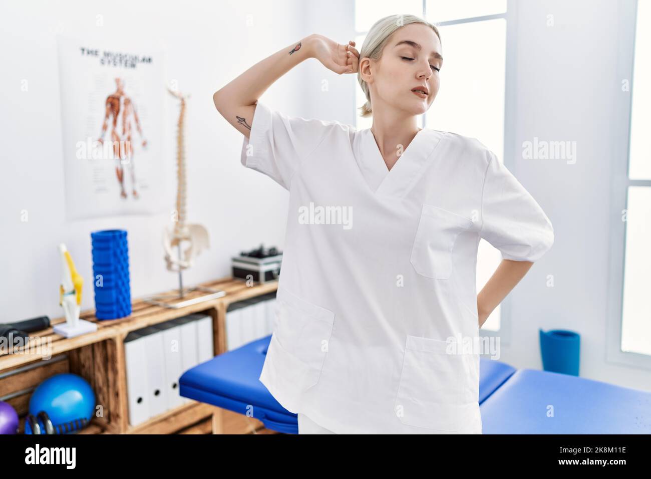 Young caucasian woman working at pain recovery clinic stretching back ...
