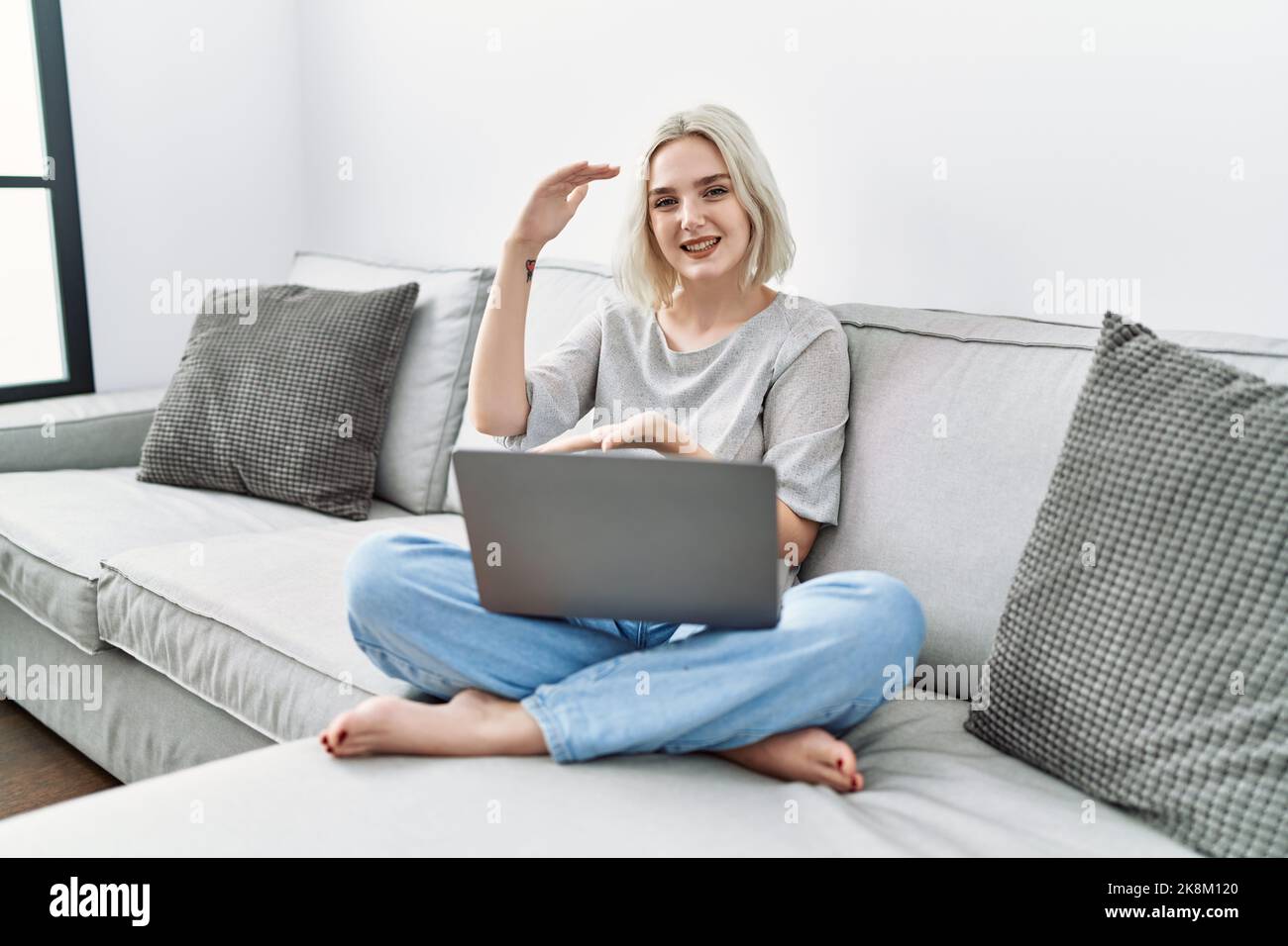 Young caucasian woman using laptop at home sitting on the sofa ...